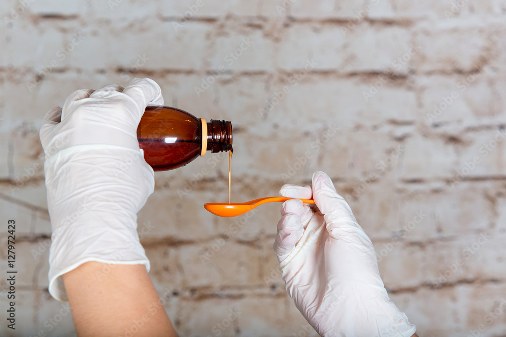 Paramedic poured from a bottle into a spoonful of cough syrup, pain ...