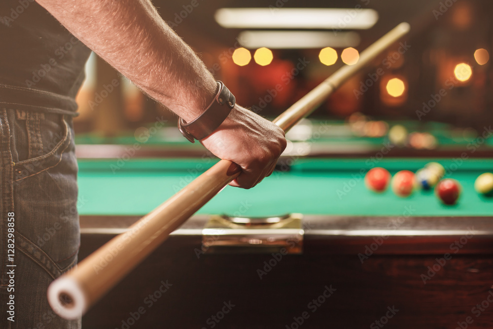 Man with cue opposite to a billiard table. Stock Photo | Adobe Stock