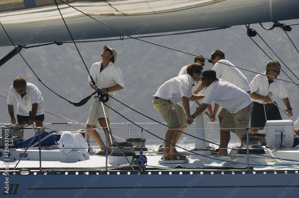 Side view of crew members working on sailboat Stock Photo | Adobe Stock