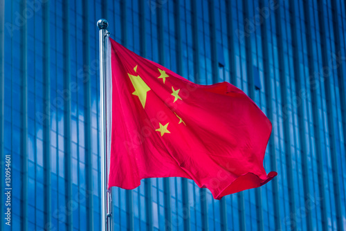 Chinese flag flying frontof futuristic skyscraper in city of China ...