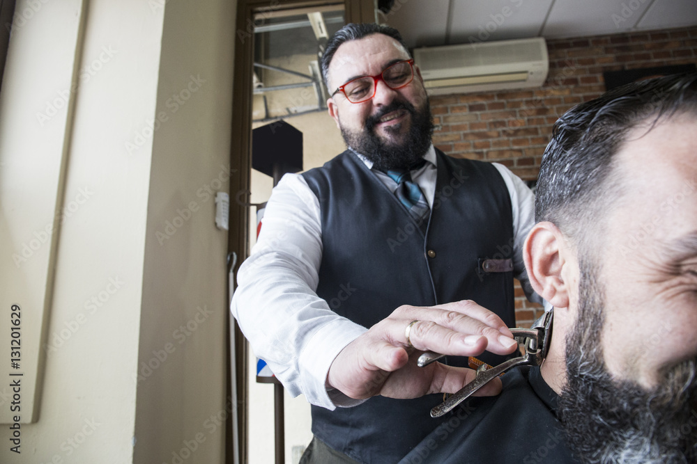 Barber cutting the hair of a man using a vintage hand operated hair ...