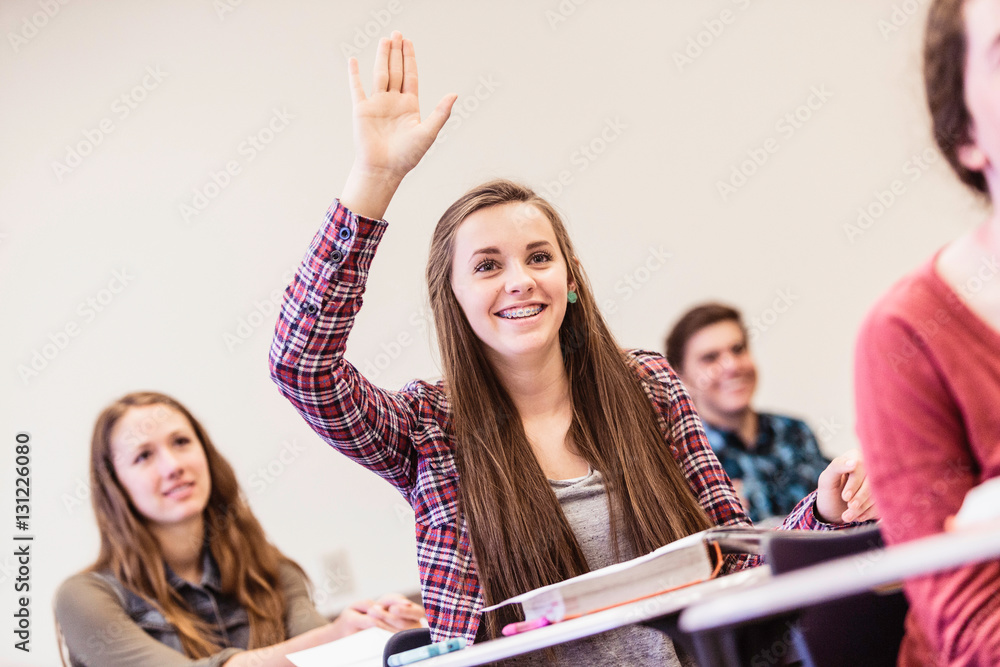 Teenage girl with hand raised in high school lesson Stock Photo | Adobe ...