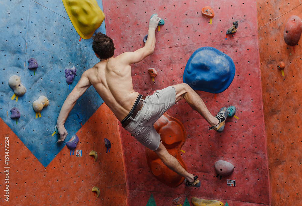 Muscular and fit topless man exercise bouldering and climbing indoor at ...