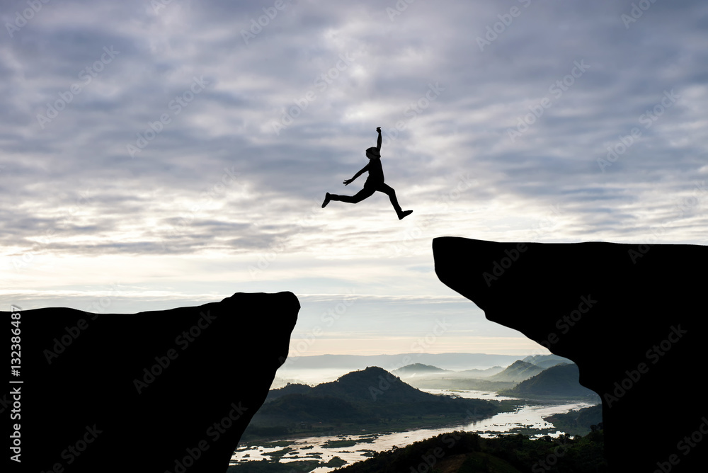Man jump through the gap between hill.man jumping over cliff on sunset ...