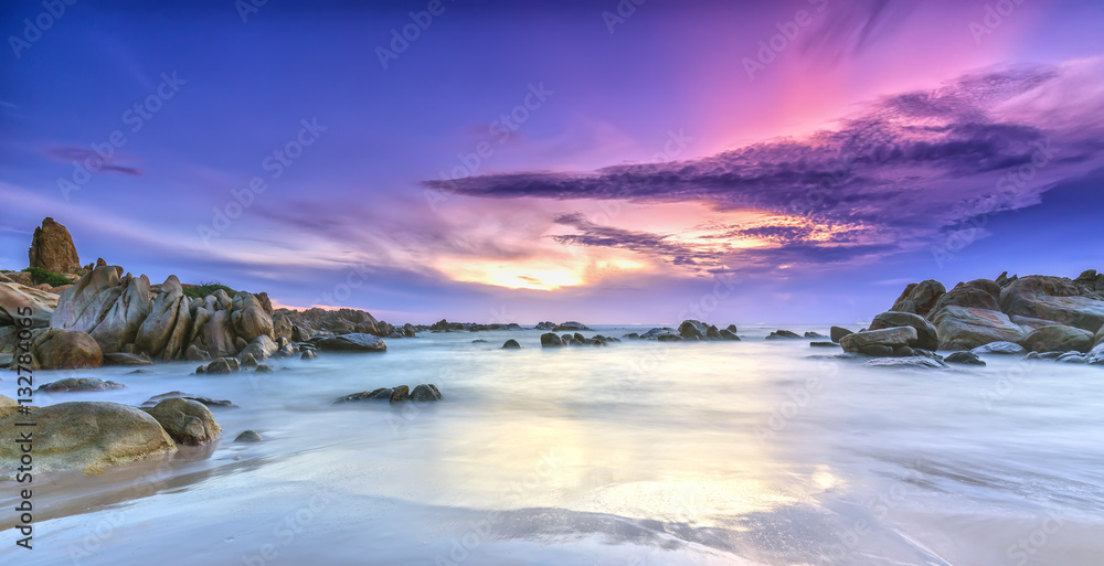 ภาพถ่าย Stock Dawn on the beach with brightly colored clouds, beneath a ...