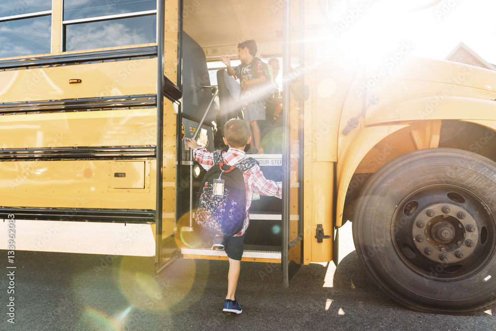 Rear view of school boy stepping on school bus Stock Photo | Adobe Stock