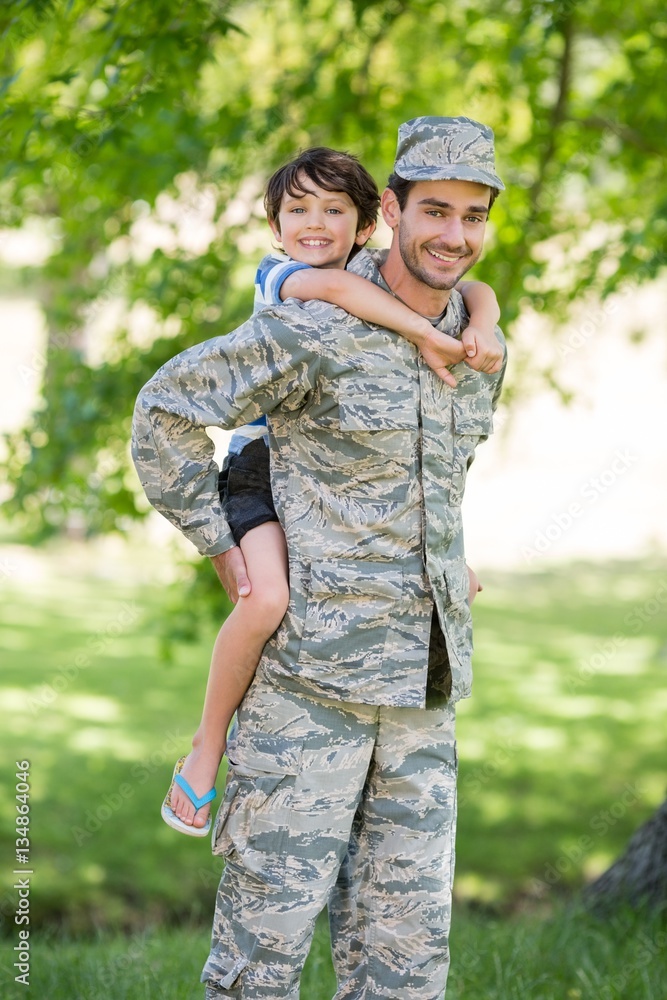 Portrait of army soldier giving piggyback ride to boy in park Stock ...
