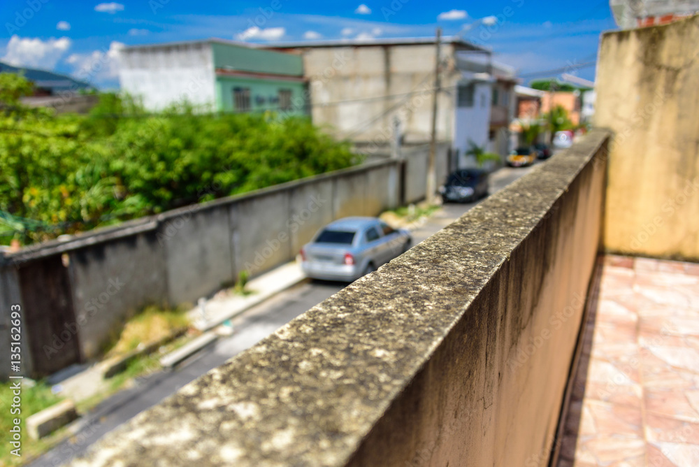The moldy wall and blurry street with cars and houses in Bangu ...