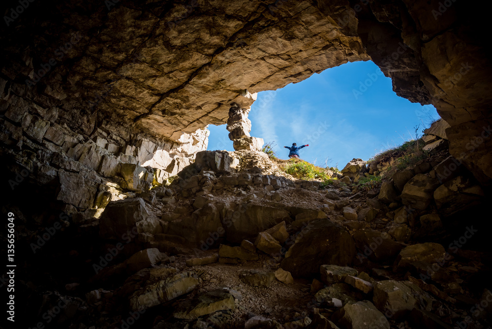 Young boy standing in front of a cave entrance Stock Photo | Adobe Stock