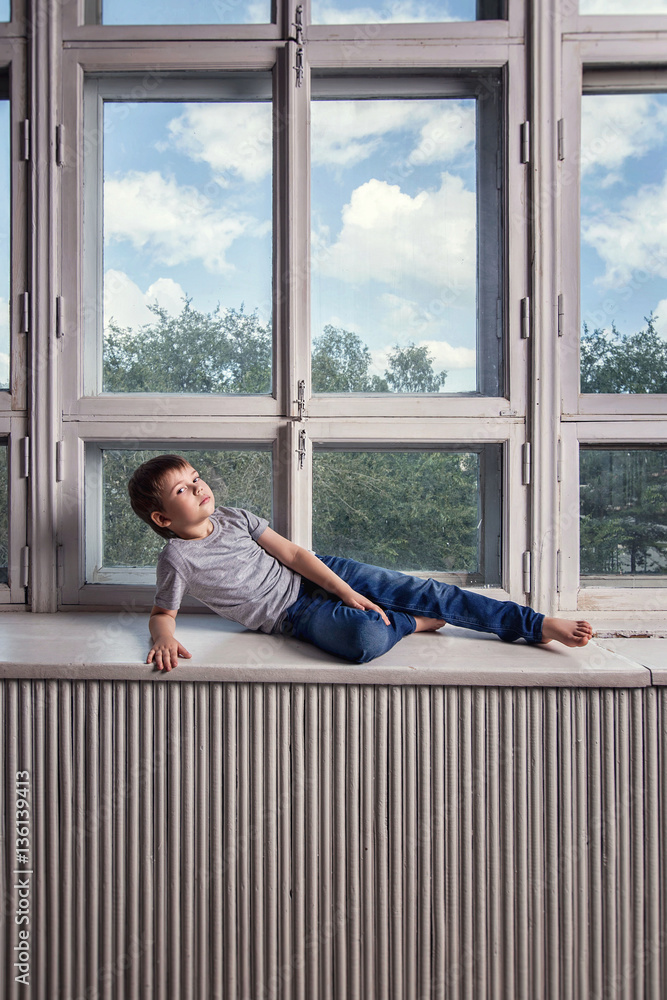 Little handsome boy in jeans and a grey shirt, barefoot, lying and ...