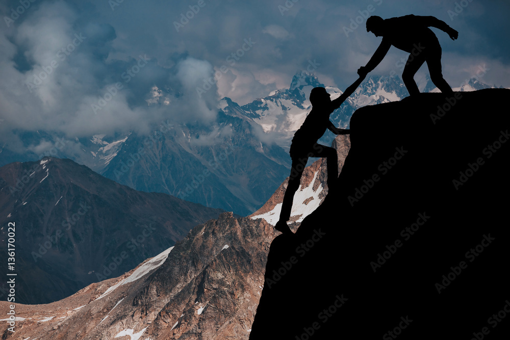 Male and female hikers climbing up mountain cliff and one of them ...