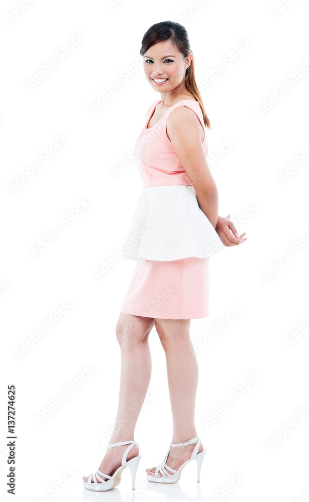 Young woman in pink dress with hands behind back on white background ...