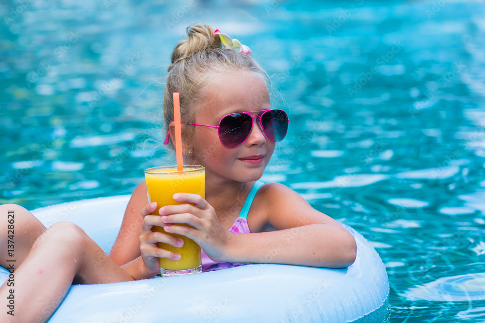 Little girl lying on inflatable ring in swimming pool. In the hands of ...