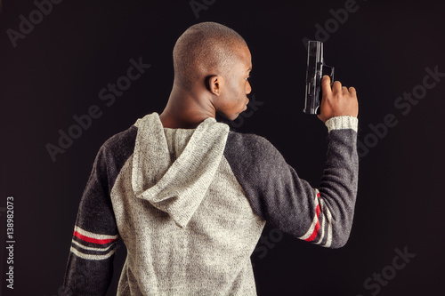 Young handsome black man holding a hand gun, on dark background in ... Young handsome black man holding a hand gun, on dark background in ...
