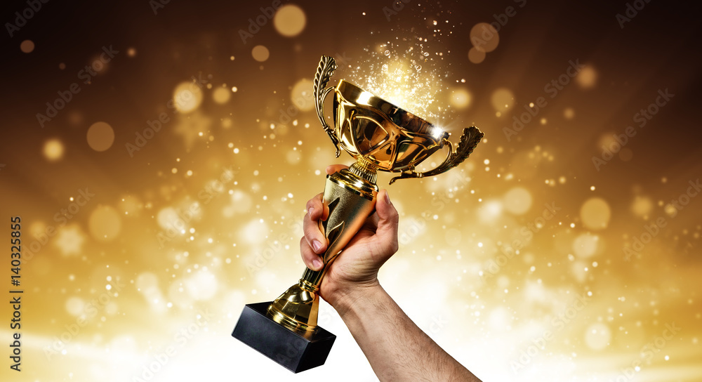 Man holding up a gold trophy cup Stock Photo | Adobe Stock