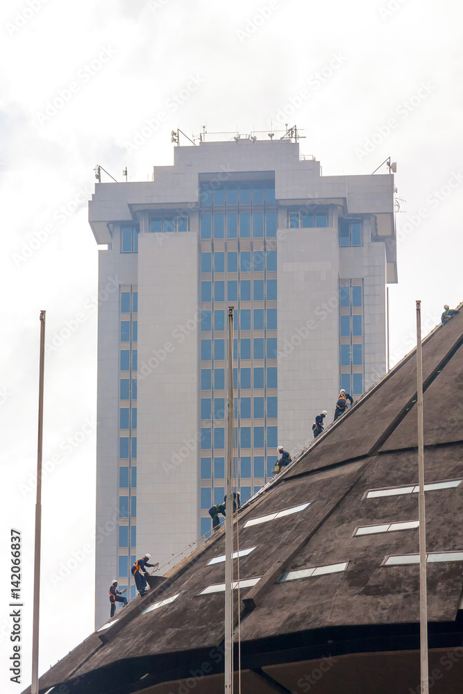 Washermen alpinists on hipped roof wash high-rise building windows ...