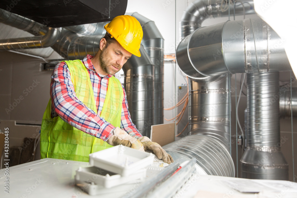 Worker making final touches to HVAC system. HVAC system stands for ...