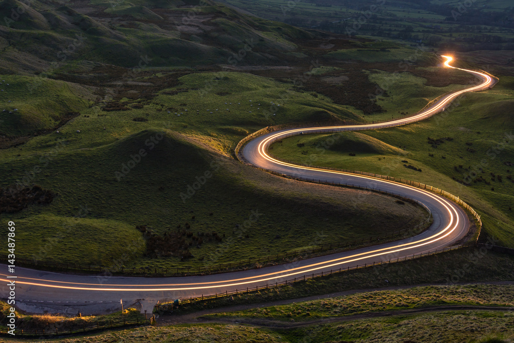Winding curvy rural road with light trail from headlights leading ...