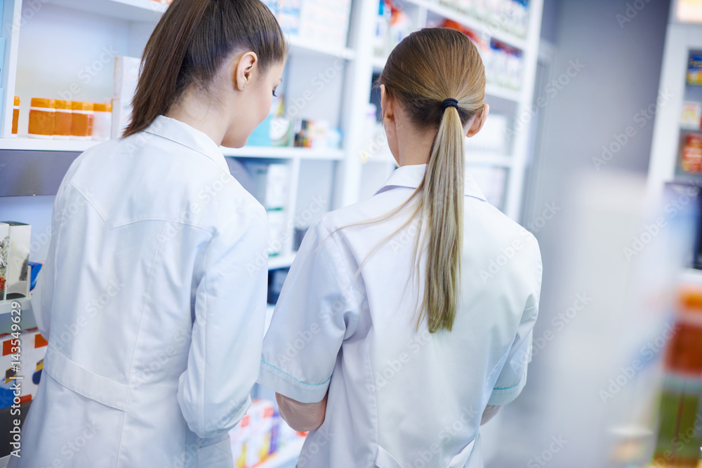 Back view of pharmacists wearing lab coats. Stock Photo | Adobe Stock