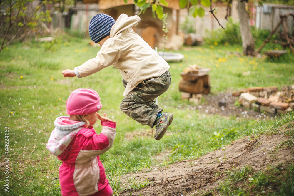 Young kids playing on the backyard - jumping from the ground slope ...