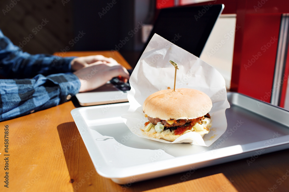 Eating at work place - fast food. burger near laptop. lunch break while ...