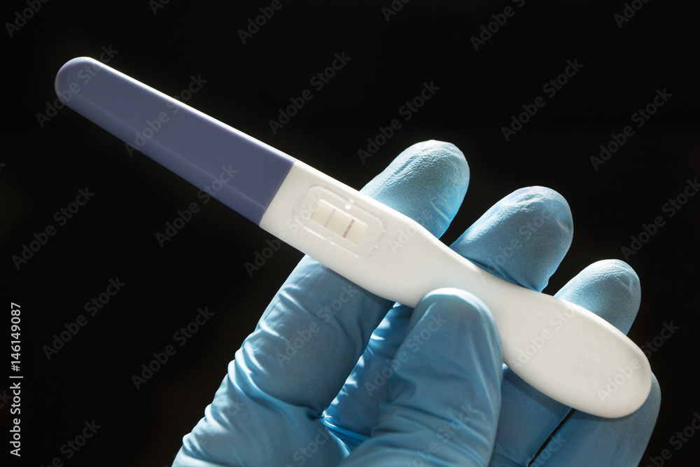 Positive pregnancy test with two strips in the hand in a blue medical ...
