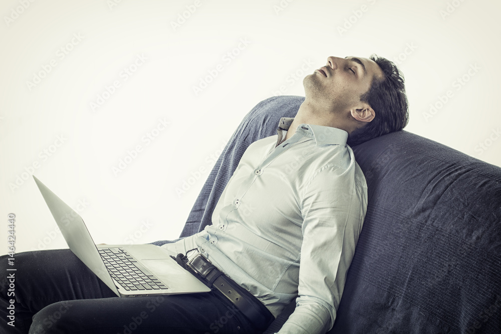 Young attractive man sleeping while working with computer sitting on ...