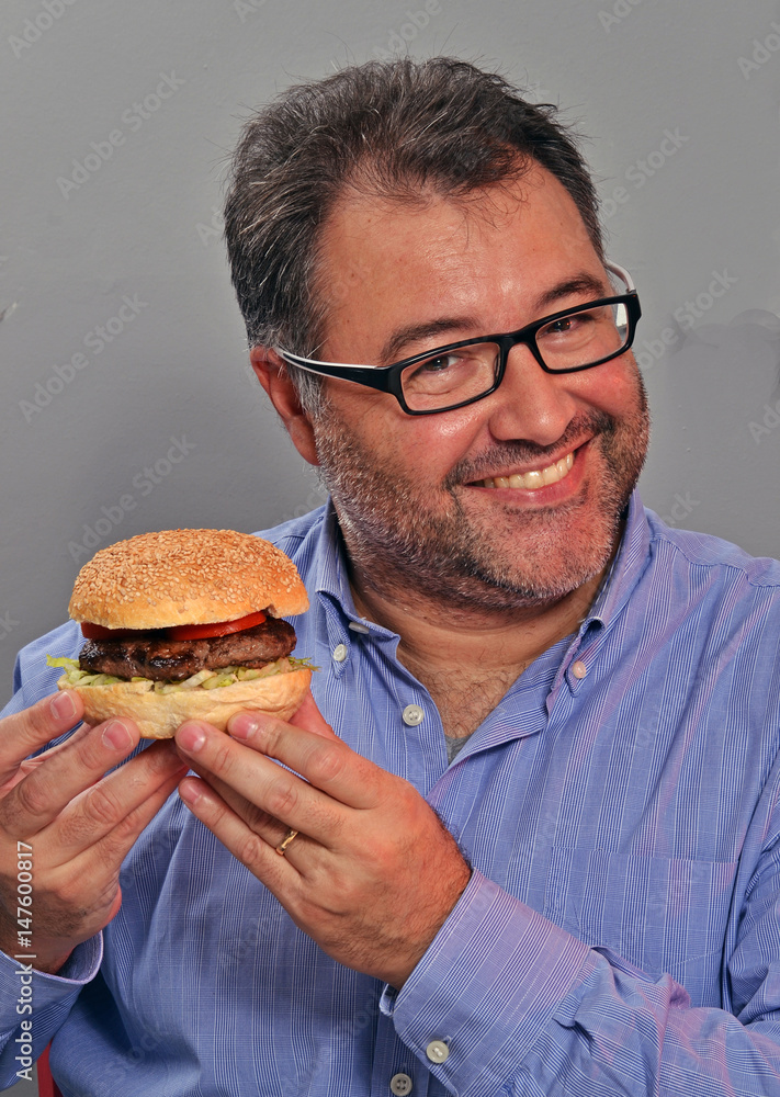 Hombre gordo feliz comiendo hamburguesa y patatas fritas. Stock Photo ...