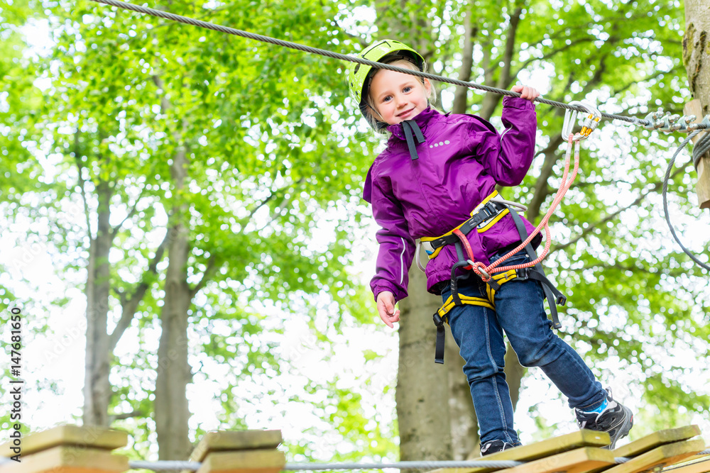 Foto stock di Girl climbing in high rope course | Adobe Stock