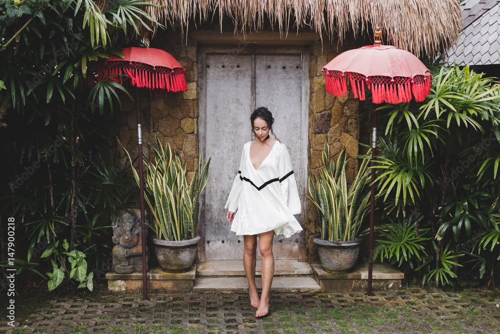 Young woman in white tunic in Ubud village with traditional balinese ...
