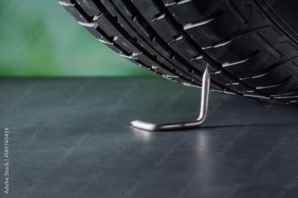 Tire spikes with car tire and green nature background at back, Bend and ...