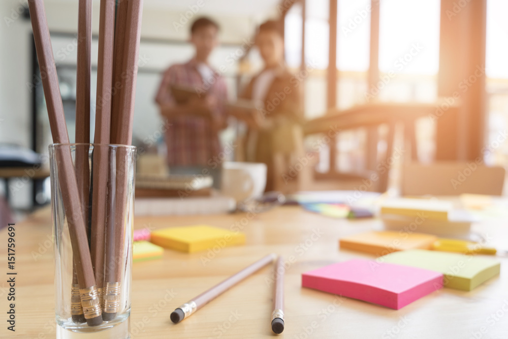 pencil and sticky note on table with background of young university ...