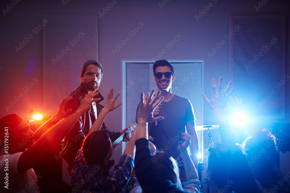 Handsome musicians performing on stage of urban club with crowd of ...