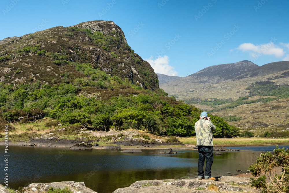 Male tourist, rear view taking pictures of Killarney National Park on ...