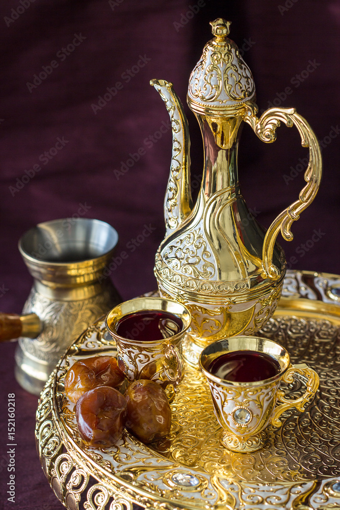 Traditional golden Arabic coffee set with dallah, coffee pot and dates ...