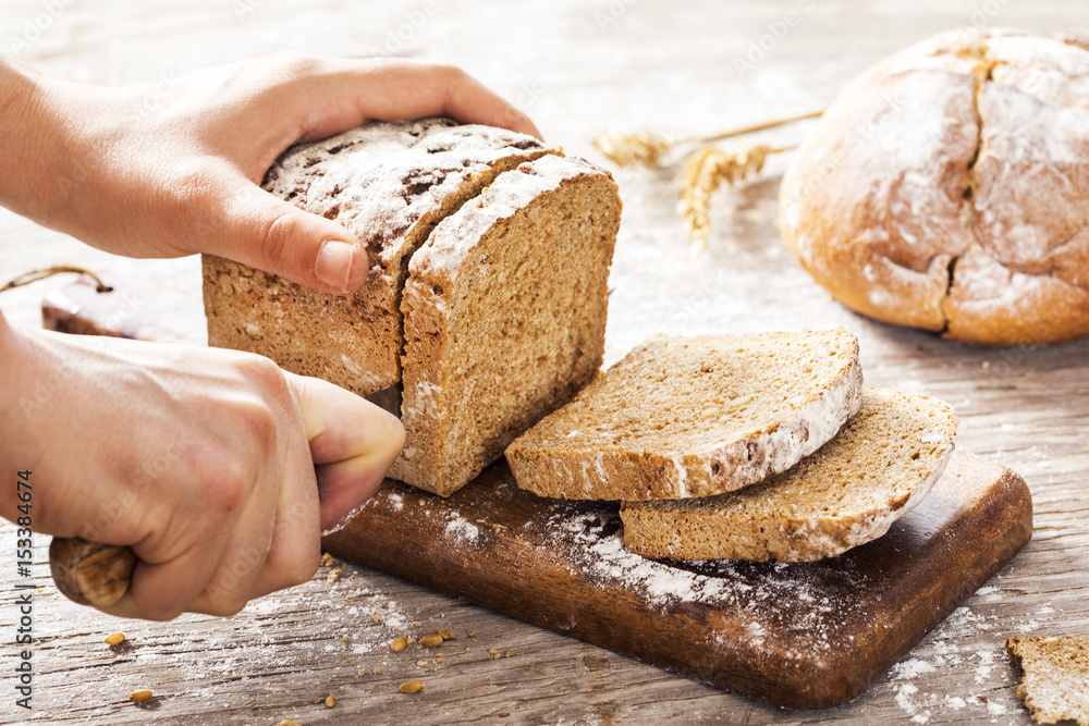 Female hands cutting whole wheat bread Stock Photo | Adobe Stock