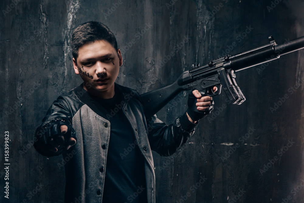 Tattooed face guy with sniper rifle pointing. Armed asian killer man ...