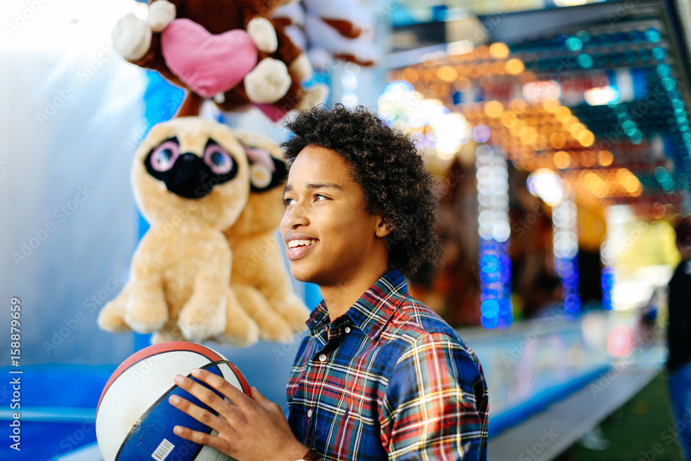 Young boy at funfair, playing on fairground stall, holding basketball ...