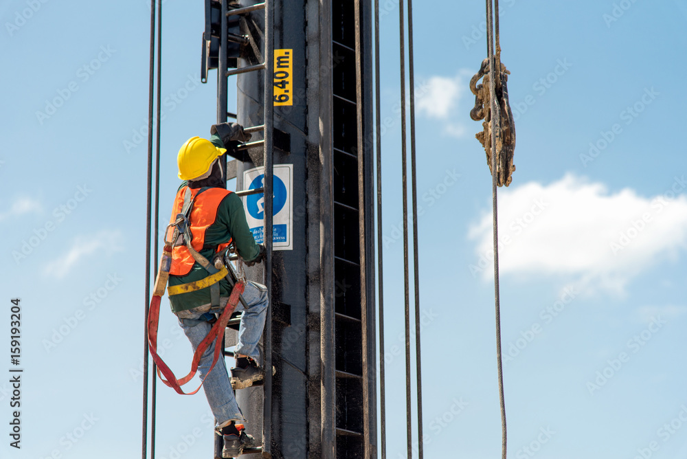 Construction workers wearing safety harness and adequate safety gear ...
