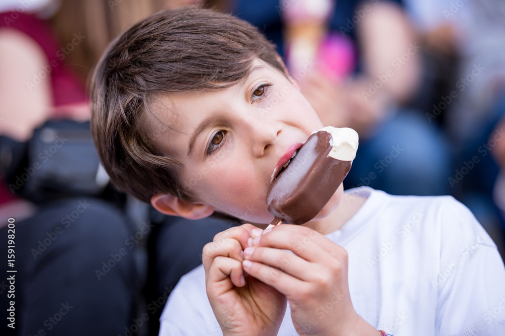 Cute young boy eating an ice cream in stadium Stock Photo | Adobe Stock