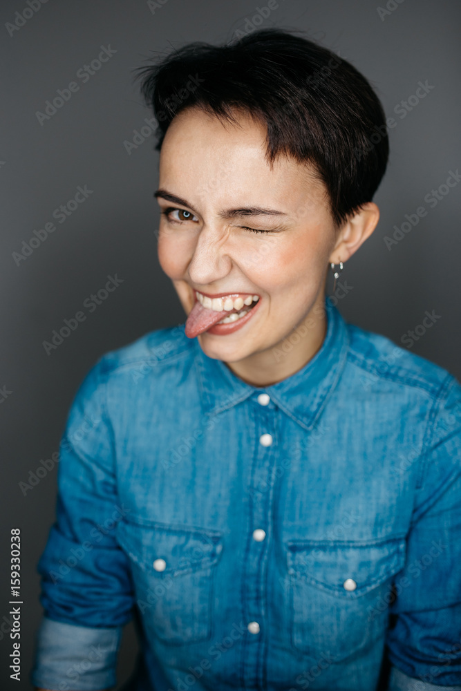 Beautiful, young girl with a mischievous expression shows her tongue at ...