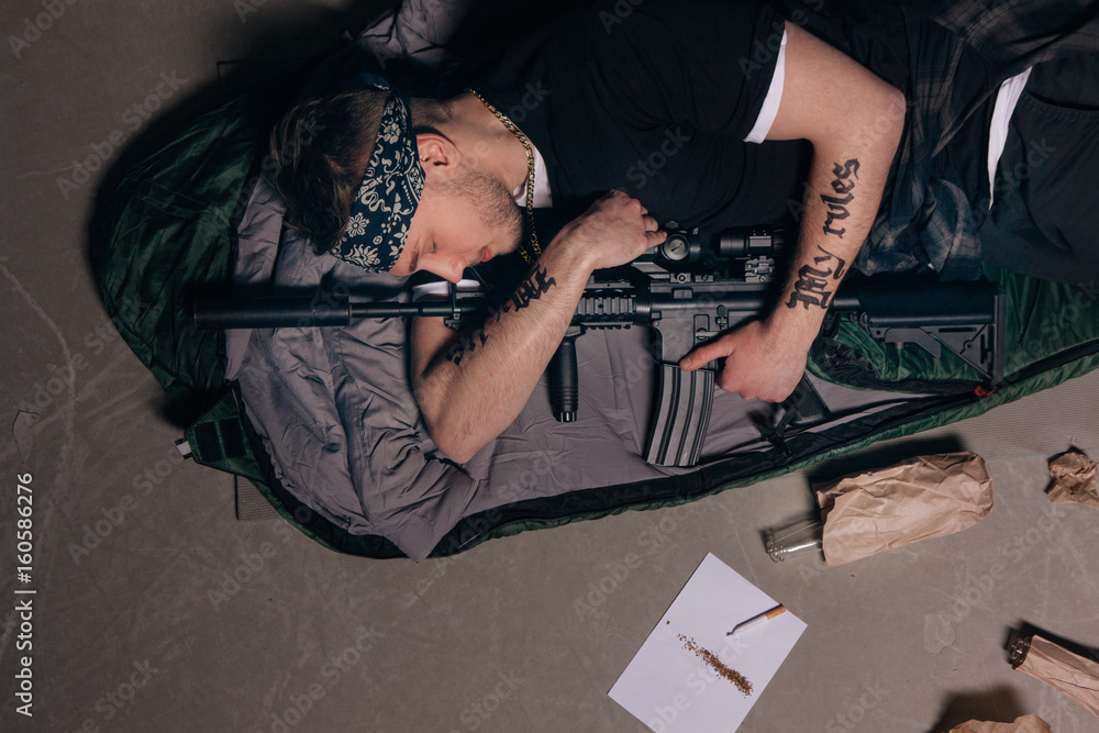 Gangster sleep with rifle. Gang wars concept. Cigarette, alcohol ...