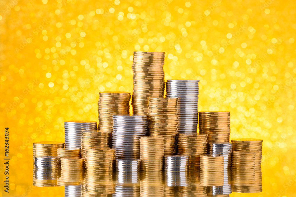 Shiny golden and silver coins stacked on gold glitter bokeh background ...