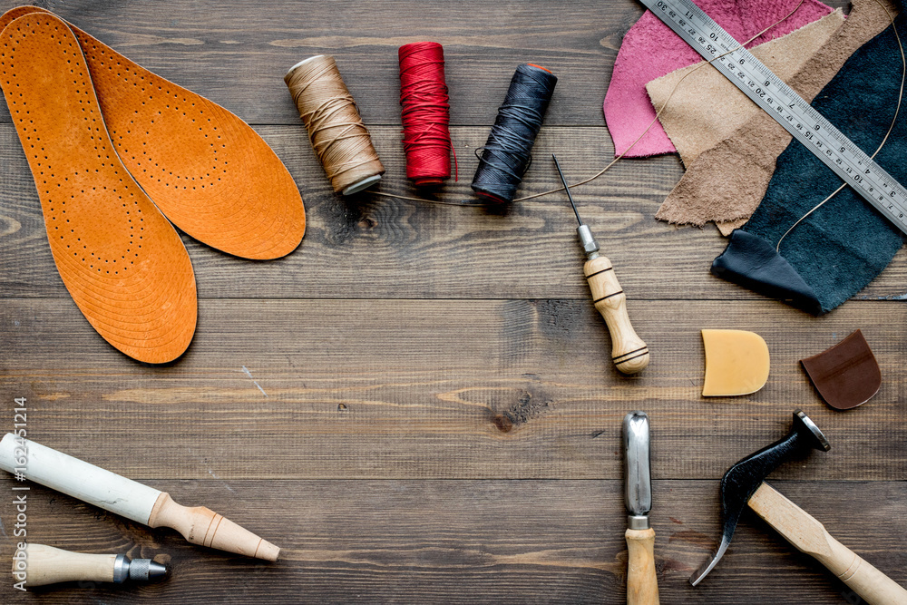 Working place of shoemaker. Skin and tools on brown wooden desk ...