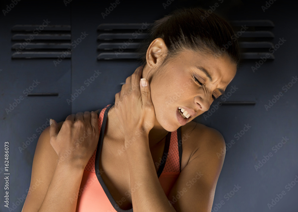 attractive hispanic fitness woman touching and grabbing her neck and ... attractive hispanic fitness woman touching and grabbing her neck and ...