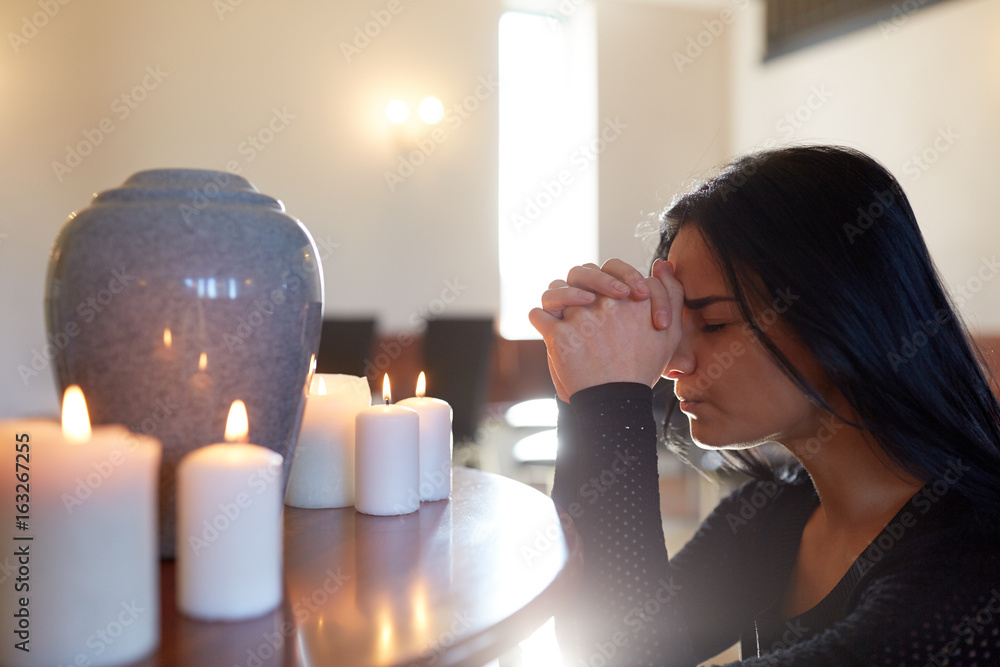 sad woman with funerary urn praying at church Stock Photo | Adobe Stock