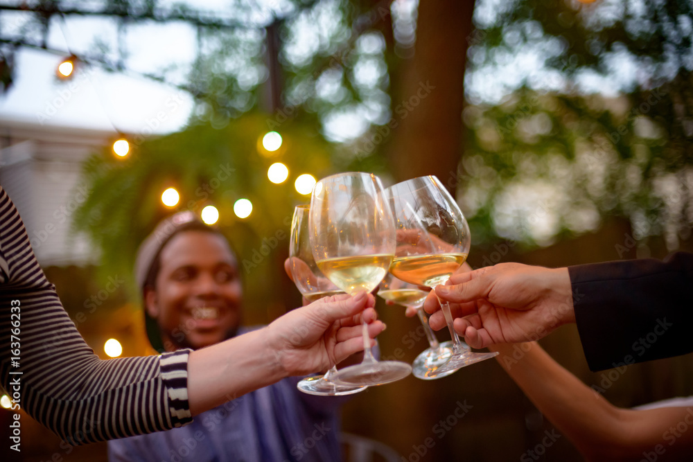 Group of people at garden party, holding wine glasses, making a toast ...