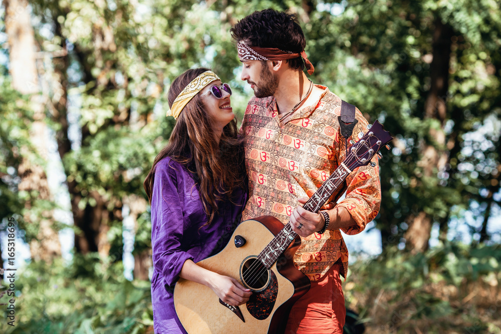 Beautiful young couple in love in hippie style with the guitar resting ...