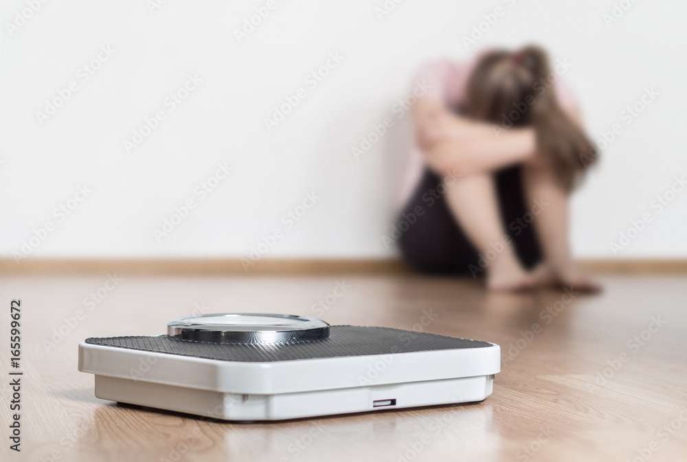 Weight loss fail concept. Scale and depressed, frustrated and sad woman ...
