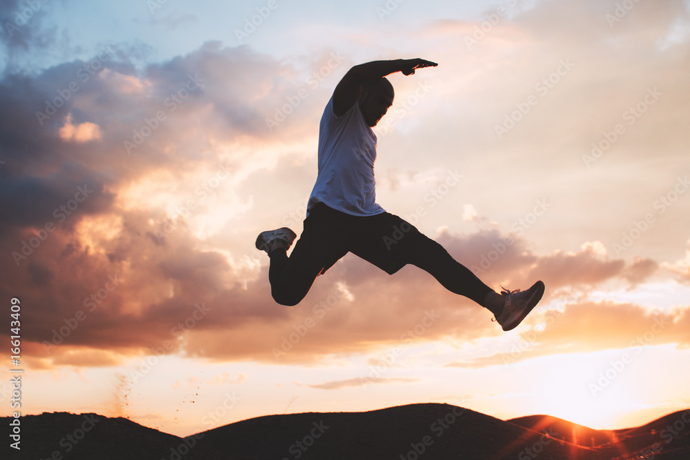 Strong and brave athlete jumps over a ditch. Silhouette of a man at the ...